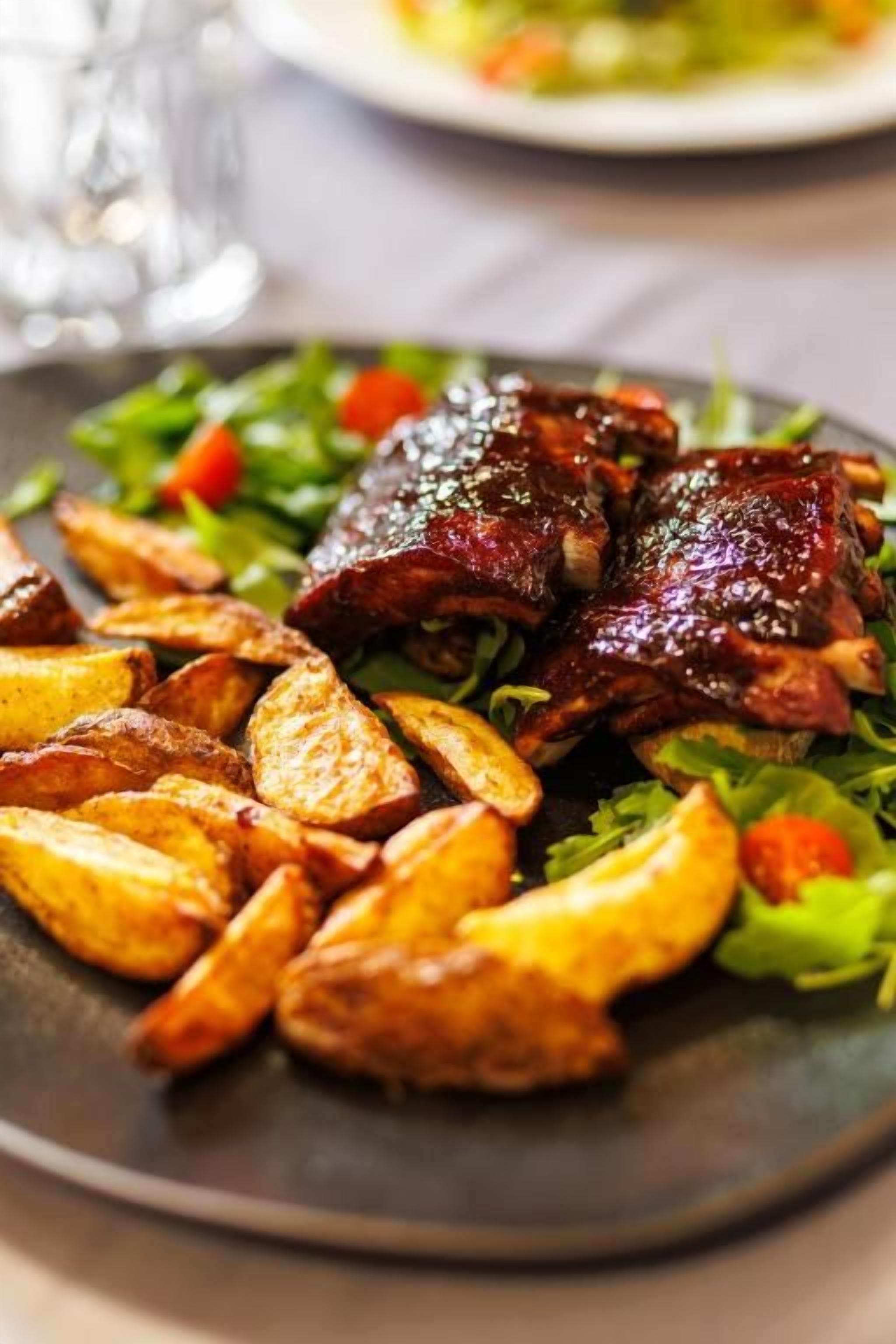 Um prato com carne assada e batatas.