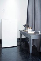 Uma cozinha compacta com geladeira branca, cafeteira e uma pequena mesa com um livro e copos.