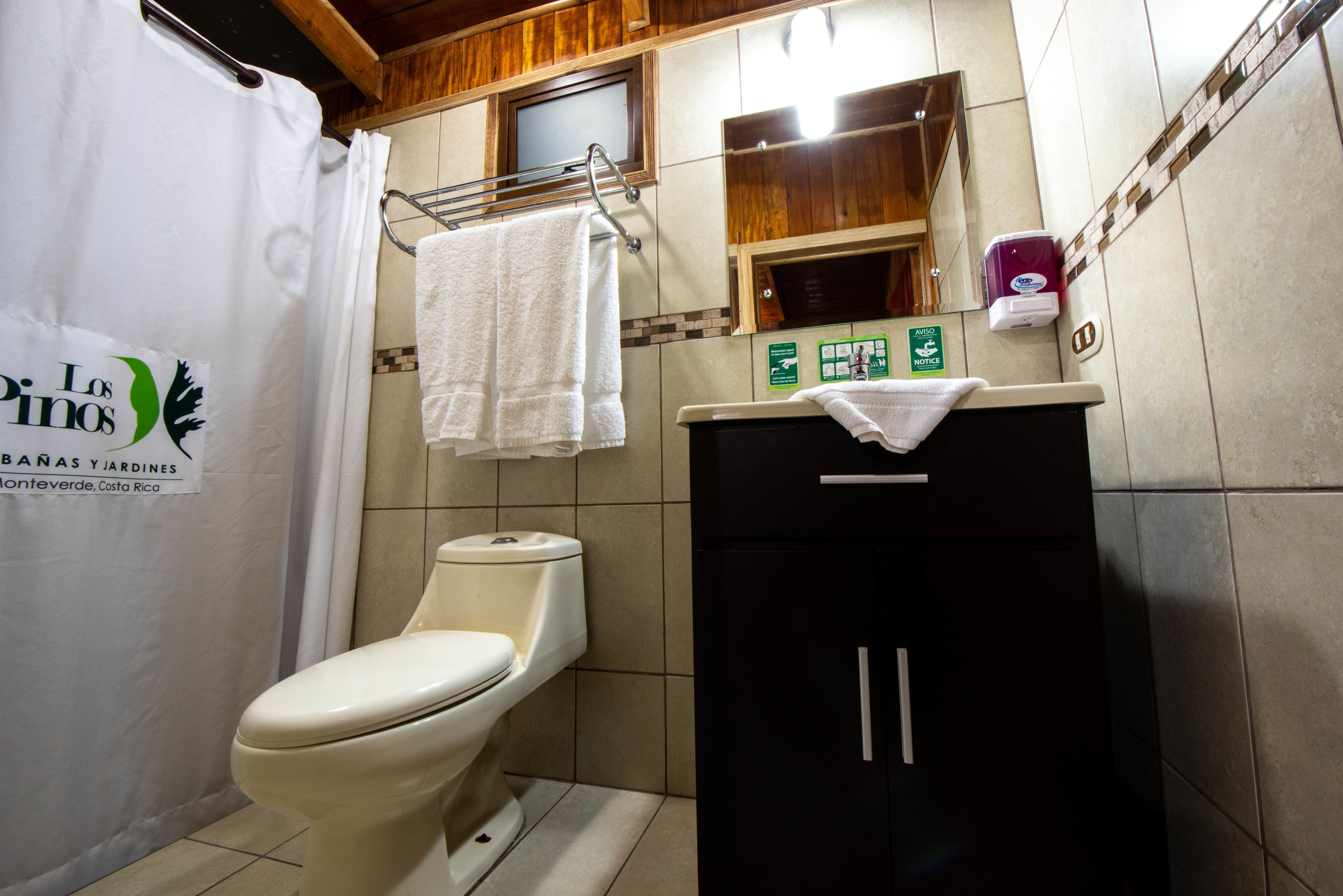 Um banheiro com vaso sanitário, porta-toalhas, pia e dispensador de sabonete.