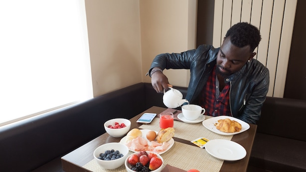Mesa de café da manhã com diversos alimentos e um smartphone.