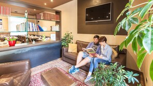 Uma sala de estar moderna com um sofá de couro marrom, uma mesa de centro de vidro e uma estante repleta de livros.