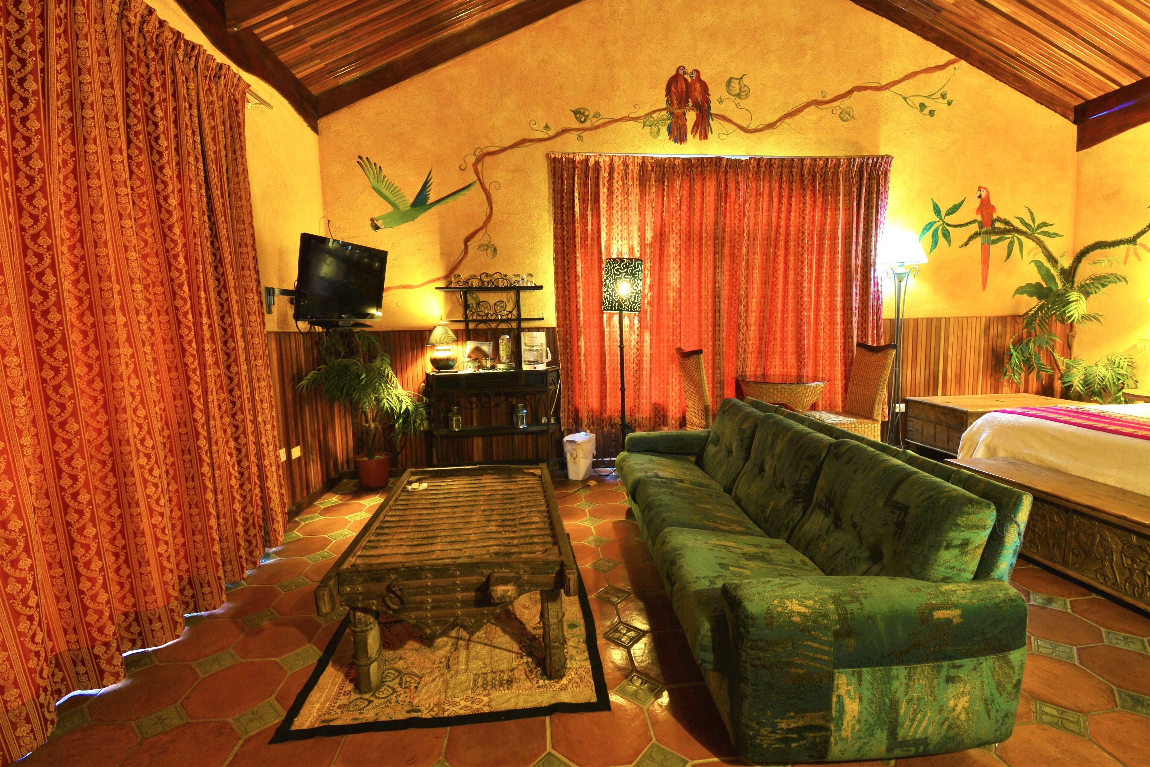 Uma sala de estar acolhedora com um sofá verde, uma mesa de centro de madeira e uma televisão sobre um suporte.