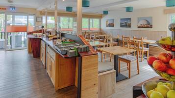 Restaurante moderno com mobiliário de madeira, uma seleção de frutas e grandes janelas.