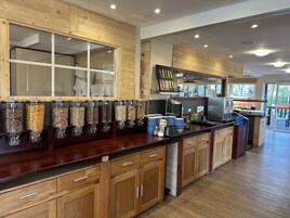 Cozinha moderna com armários de madeira, uma ilha central com máquina de café e janela com vista para um deck.
