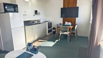Uma cozinha moderna com armários brancos, micro-ondas, cafeteira e um espaço de refeições com mesa e cadeiras.