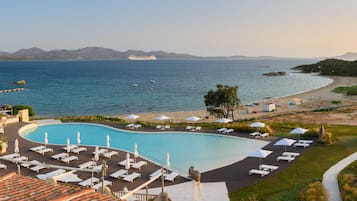 Um resort com piscina, praia e vista para as montanhas.