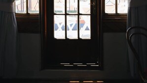 Quarto com uma janela grande, porta de madeira e cortinas.