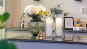 Uma área de bar com prateleiras de garrafas, um relógio, velas e um vaso de flores.