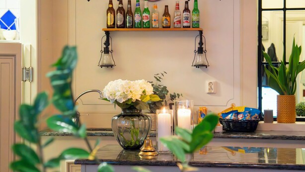 Uma cozinha com relógio, garrafas de vinho e velas.
