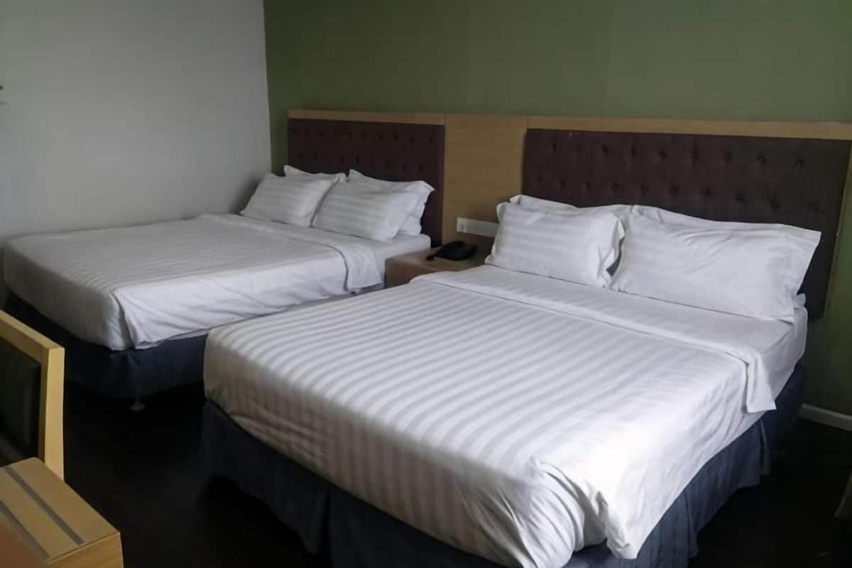 Quarto de hotel com duas camas, uma mesa de cabeceira e uma cabeceira de madeira.