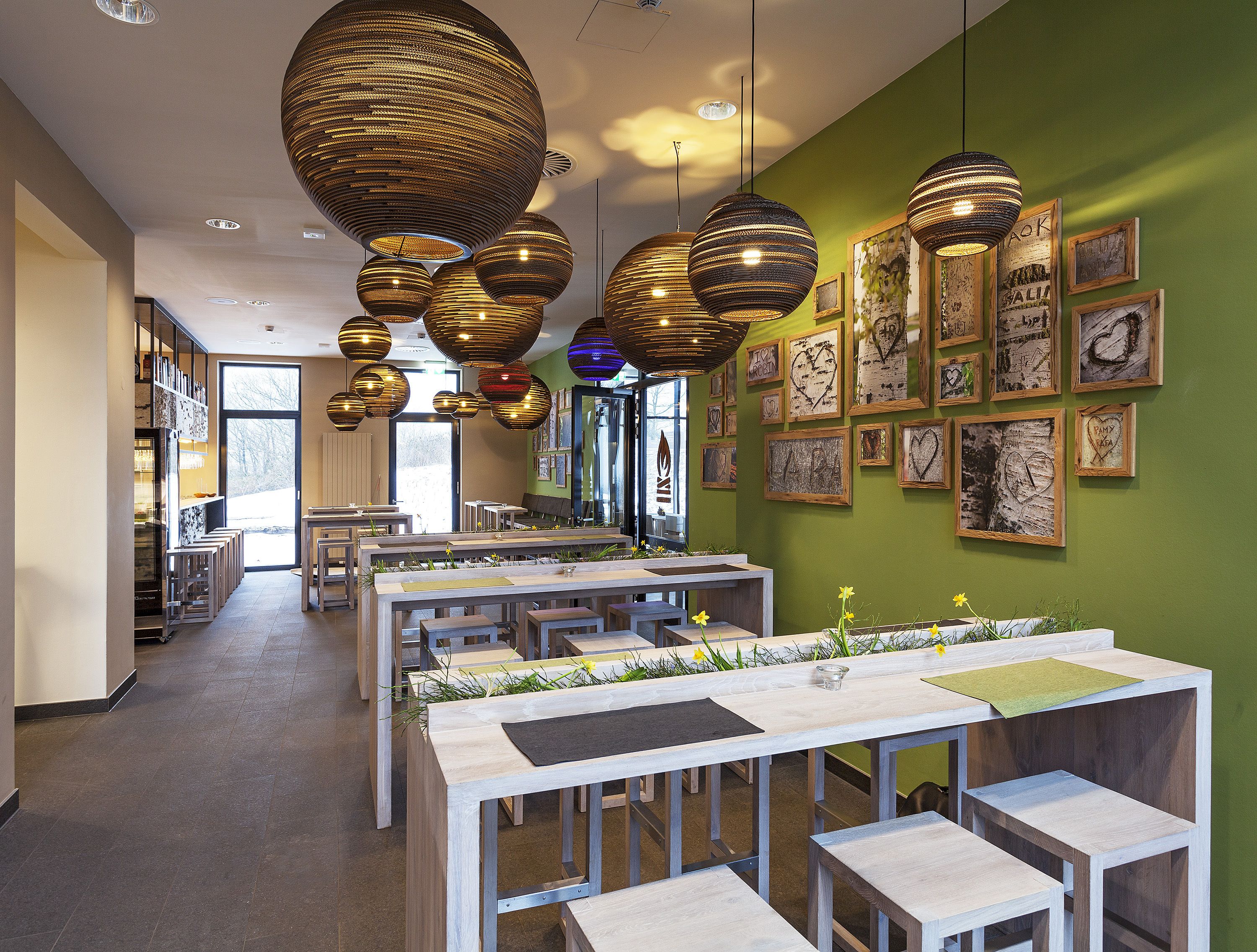 Um restaurante com várias mesas e luminárias esféricas penduradas.
