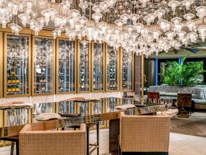 Um restaurante com um balcão comprido, várias áreas de estar e uma exibição de vinhos.