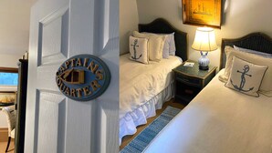 Quarto com cama, almofadas, mesa de cabeceira, abajur e placa na parede.