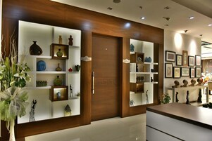 Um interior moderno com painéis de madeira, prateleiras exibindo objetos decorativos e uma porta central com design geométrico.