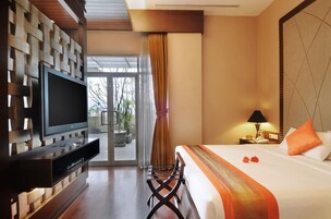 Quarto de hotel com cama, televisão, escrivaninha e vista para o exterior.