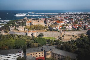 Paisagem urbana histórica com um castelo imponente, um porto com navios de cruzeiro e uma área urbana densamente construída.