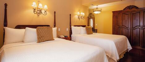Quarto de hotel com duas camas, um guarda-roupa de madeira e luminárias fixadas na parede.