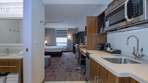 Quarto de hotel pequeno com cozinha compacta, cama, banheiro e vista para a cidade.