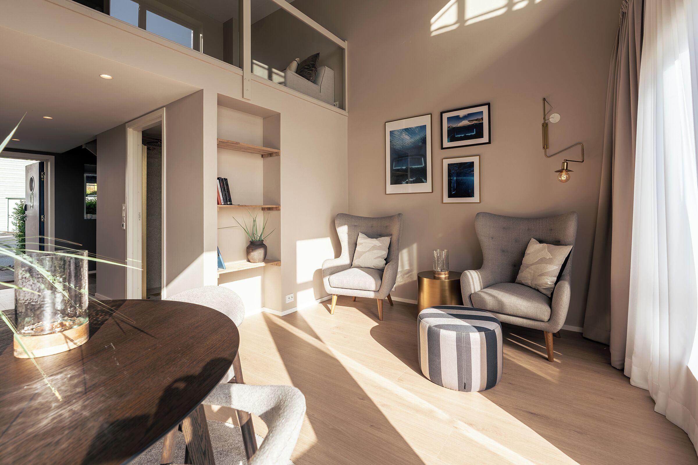 Uma sala de estar moderna com uma mesa de jantar, duas poltronas, uma mesinha de apoio e uma estante de livros.