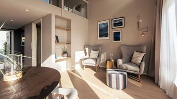 Uma sala de estar moderna com uma mesa de jantar, duas poltronas, uma mesinha de apoio e uma estante de livros.
