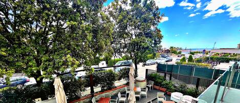 Terraço no telhado com área de estar ao ar livre, vista para carros estacionados e vegetação exuberante.