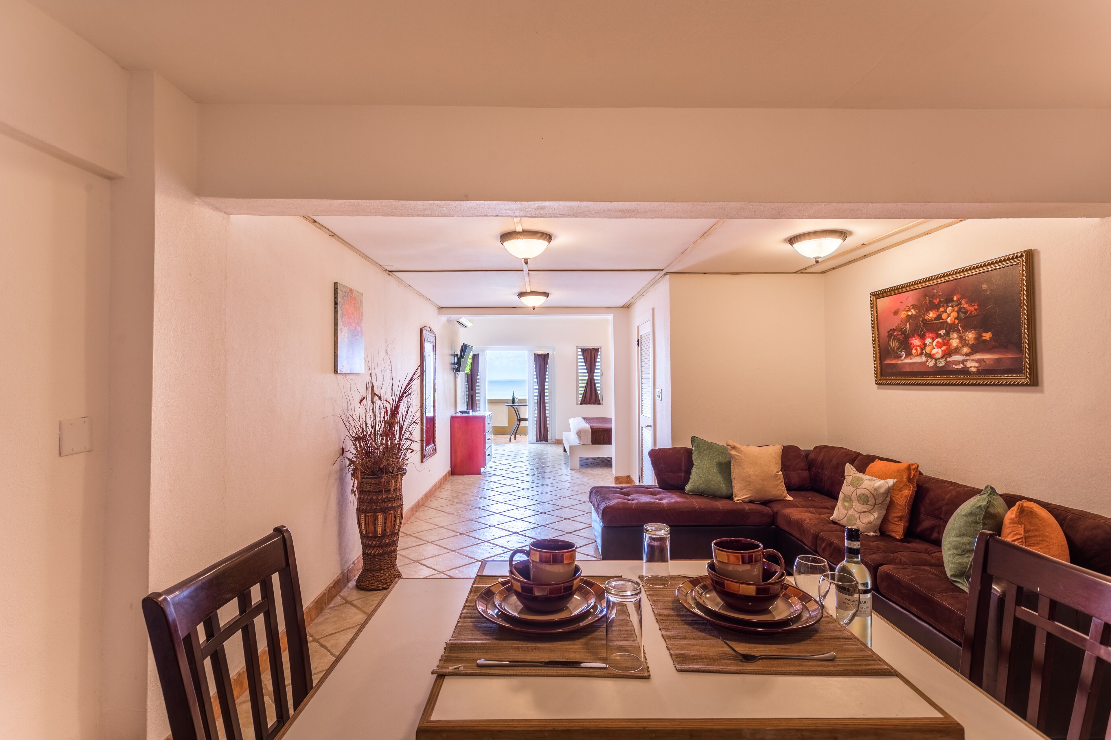 Uma área de refeições com uma mesa posta para dois, um sofá e um quadro na parede.