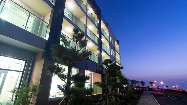Um hotel de vários andares com design moderno, caracterizado por grandes janelas e fachada bem iluminada.