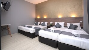 Quarto de hotel com duas camas, uma escrivaninha e televisão fixada na parede.