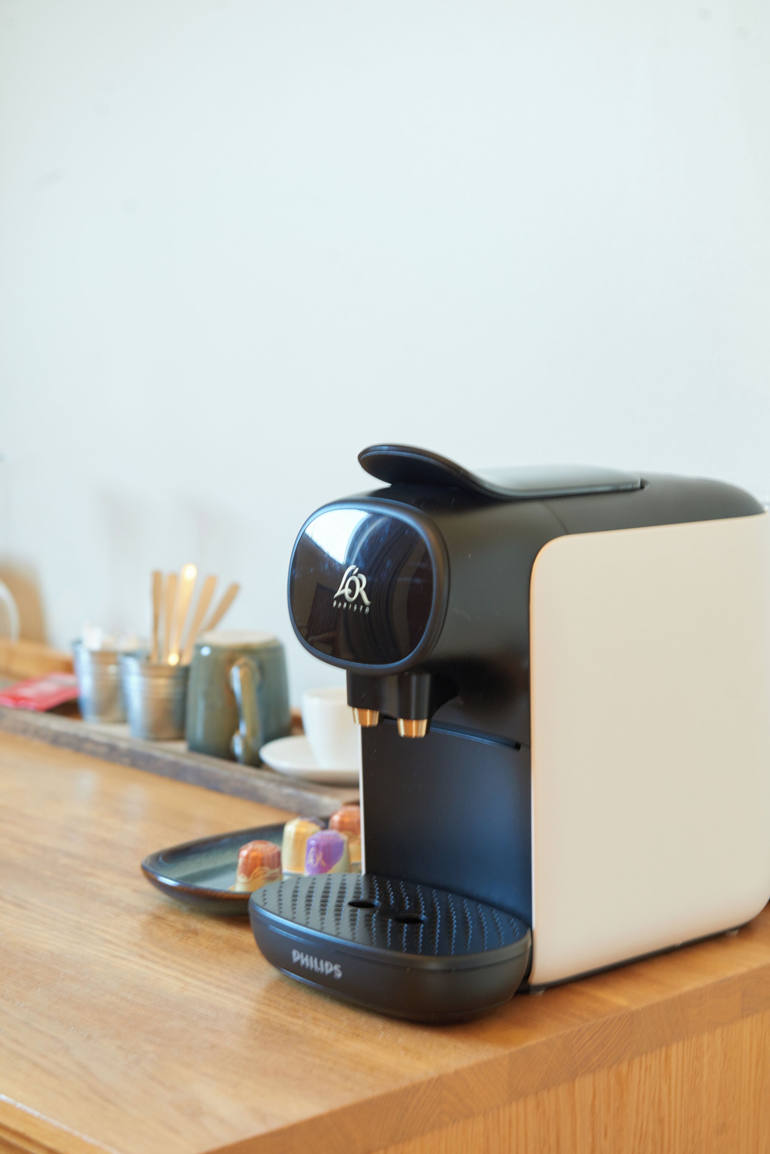 Máquina de café sobre uma mesa de madeira, com um prato de nozes e uma caneca.