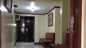 Um corredor com chão de azulejos, um banco e uma porta que dá para outro quarto.