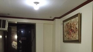 Um quarto com piso ladrilhado, um banco, um quadro na parede e um aparelho de ar condicionado.