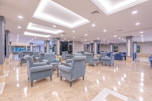 Um hall amplo com assentos modernos, piso de mármore e teto iluminado.
