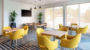 Uma sala de conferência moderna com cadeiras amarelas, uma grande mesa e plantas em vasos.