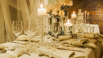 Mesa de jantar formal posta com velas, copos e um arranjo de flores.