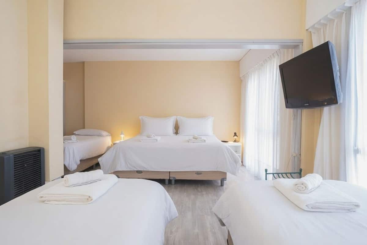 Quarto de hotel com duas camas, televisão de tela plana e janela com cortinas.