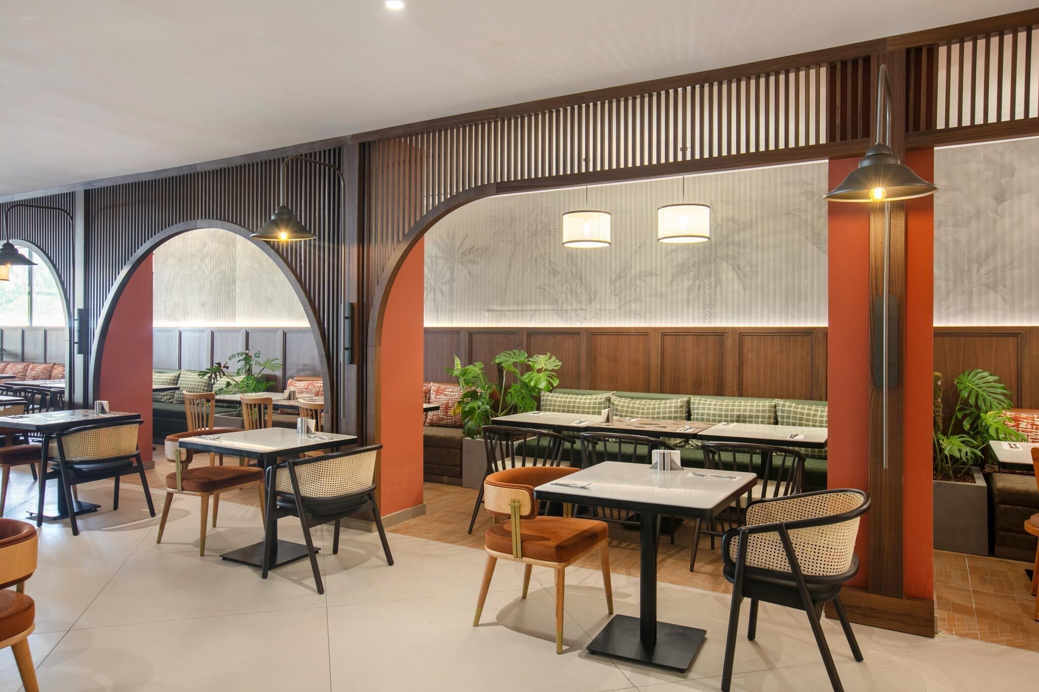 Interior de restaurante com mesas, cadeiras e teto alto com vigas de madeira.