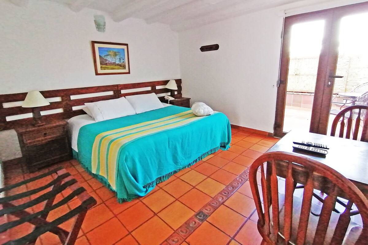 Um quarto com uma cama, mesa de cabeceira, mesa e uma cadeira.