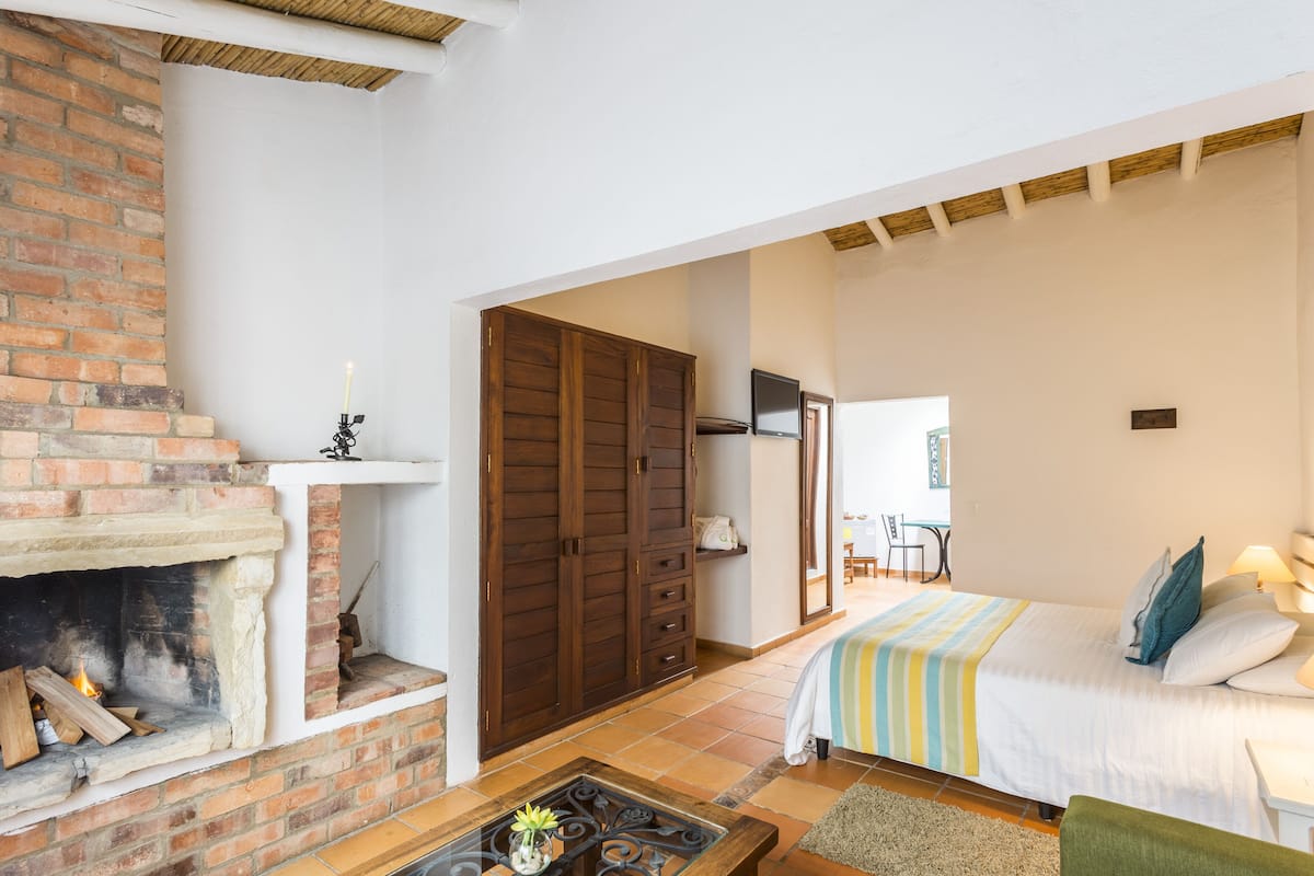 Quarto com cama, lareira, guarda-roupa de madeira e televisão.