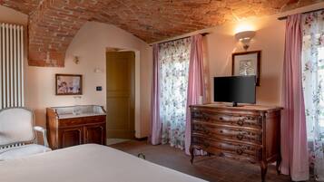 Quarto com teto de tijolos, cama, cômoda, televisão e cortinas florais.