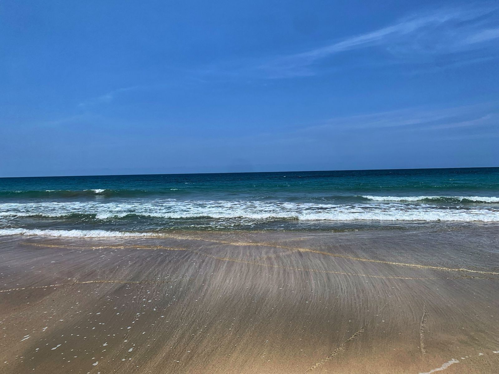 Uma praia com céu claro e ondas do mar.