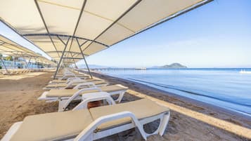 Uma praia privada, espreguiçadeiras, guarda-sóis de praia