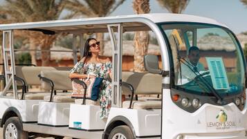 Um carrinho de golfe com uma placa que diz 'LEMON & SOUL MAKADI BAY' e uma pessoa sentada lá dentro.