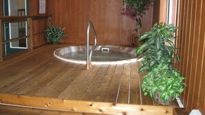 Uma área de spa com madeira, incluindo uma banheira de hidromassagem, um relógio e plantas em vasos.