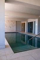 Uma piscina com muro de pedra e porta de vidro que dá para uma área de chuveiro.