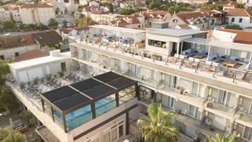 Um hotel com vários andares, piscina no terraço, áreas de estar ao ar livre e vista do bairro ao redor.