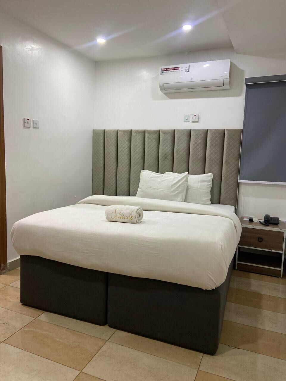 Quarto de hotel com cama, ar-condicionado fixado na parede e televisão.