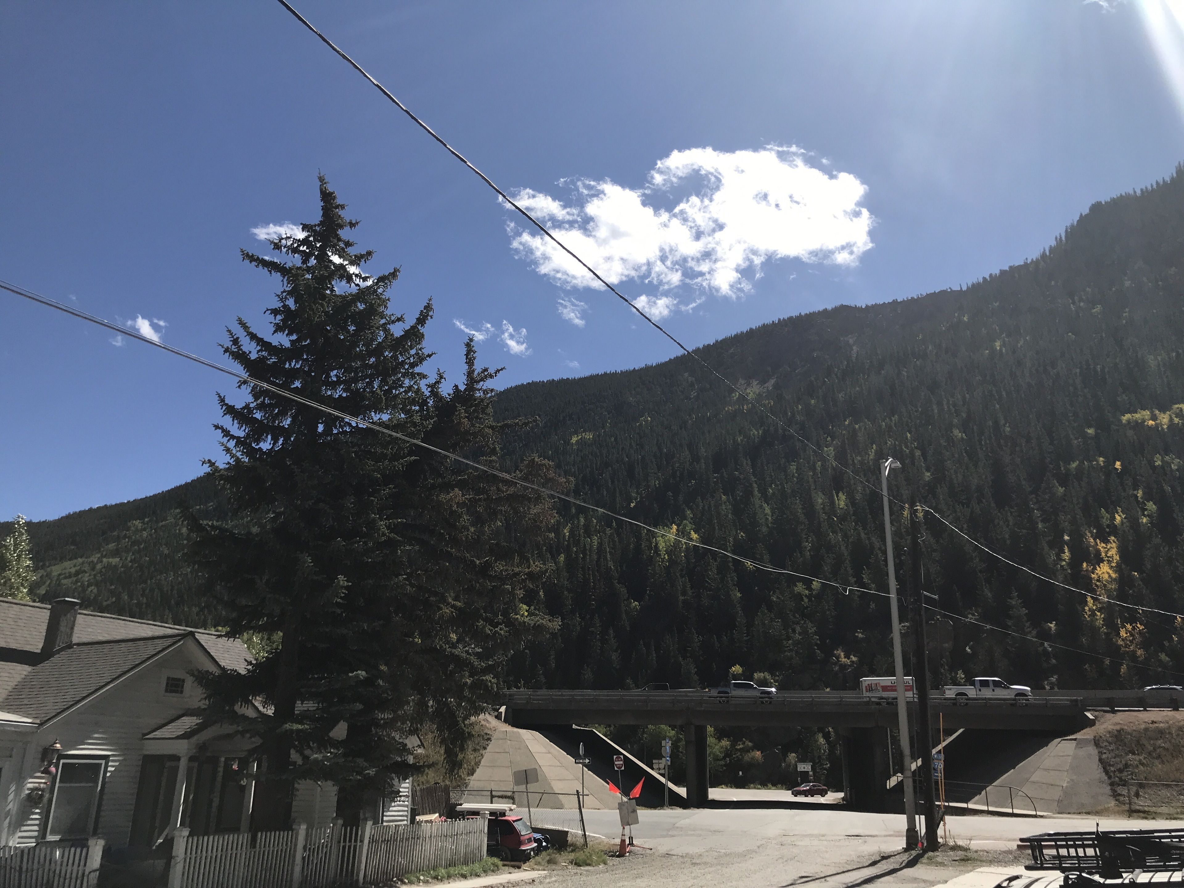 Zona residencial com uma casa, uma árvore grande e uma montanha ao fundo.