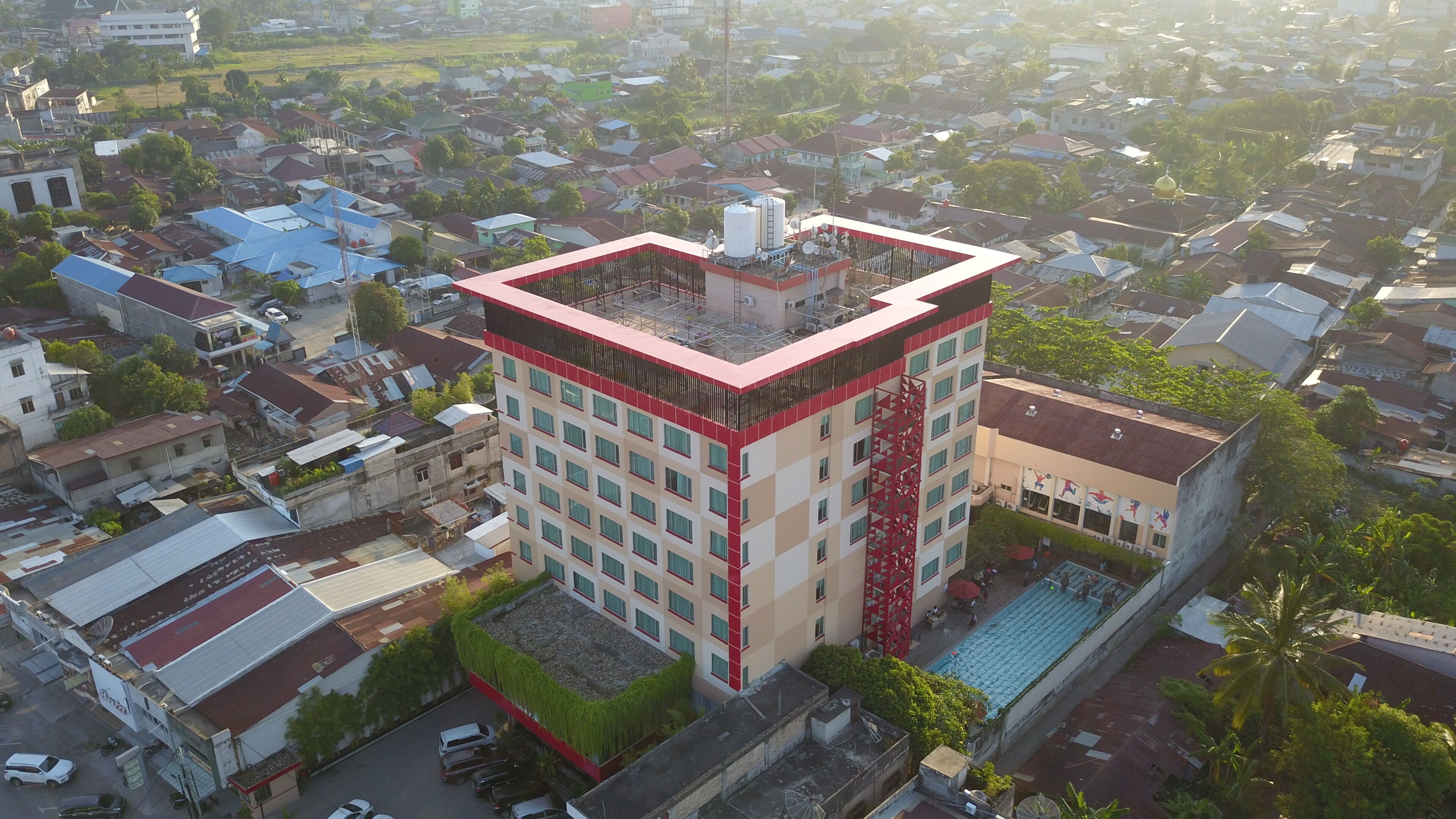 Um edifício com vários andares e terraço no telhado, rodeado por outros edifícios residenciais.