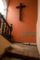 Uma escadaria com corrimão de madeira e uma cruz na parede.