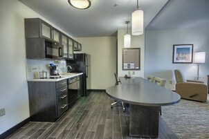 Cozinha moderna com ilha central, eletrodomésticos embutidos e área de refeições com mesa redonda.